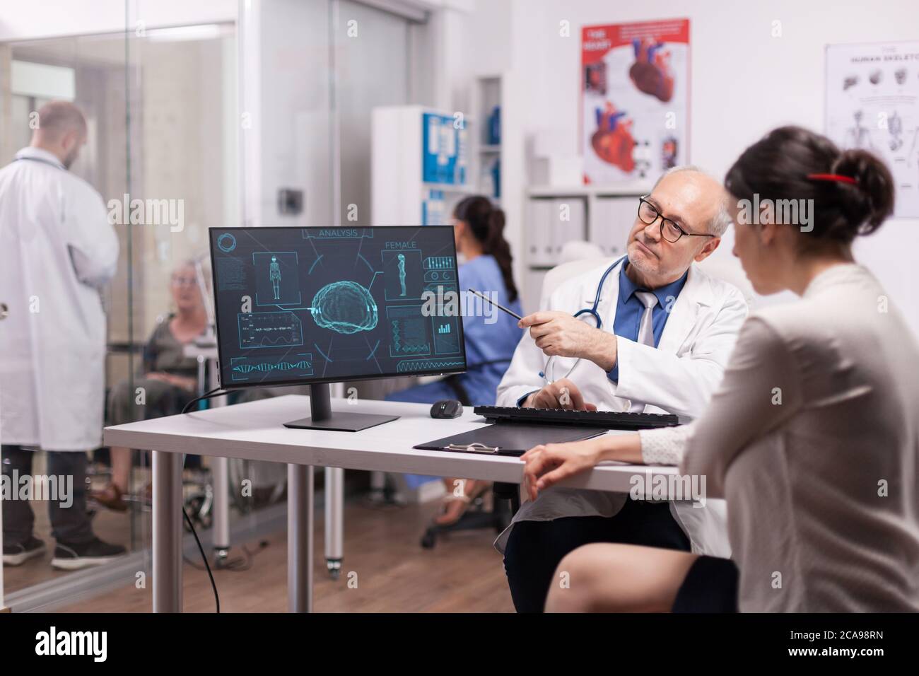 Senior doctor pointing at ct scan on computer in hospital office for ...
