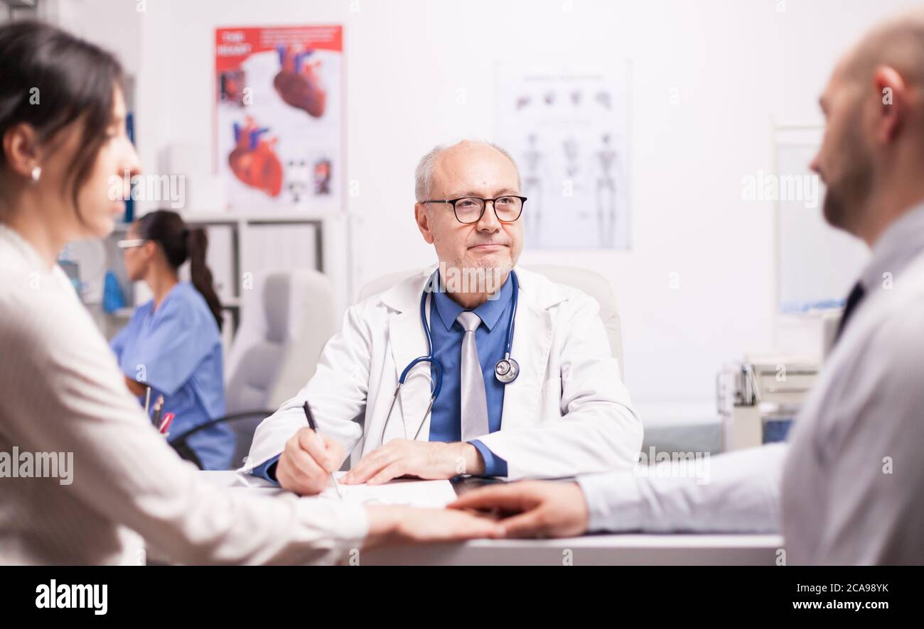 Worried couple holding hands during medical check in hospital office ...
