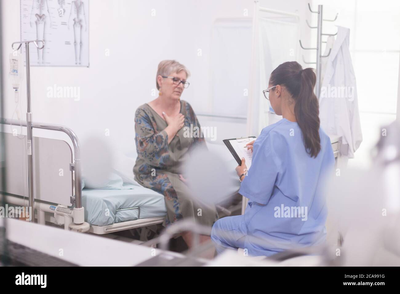 Senior patient discussing about illness with nurse during medical ...