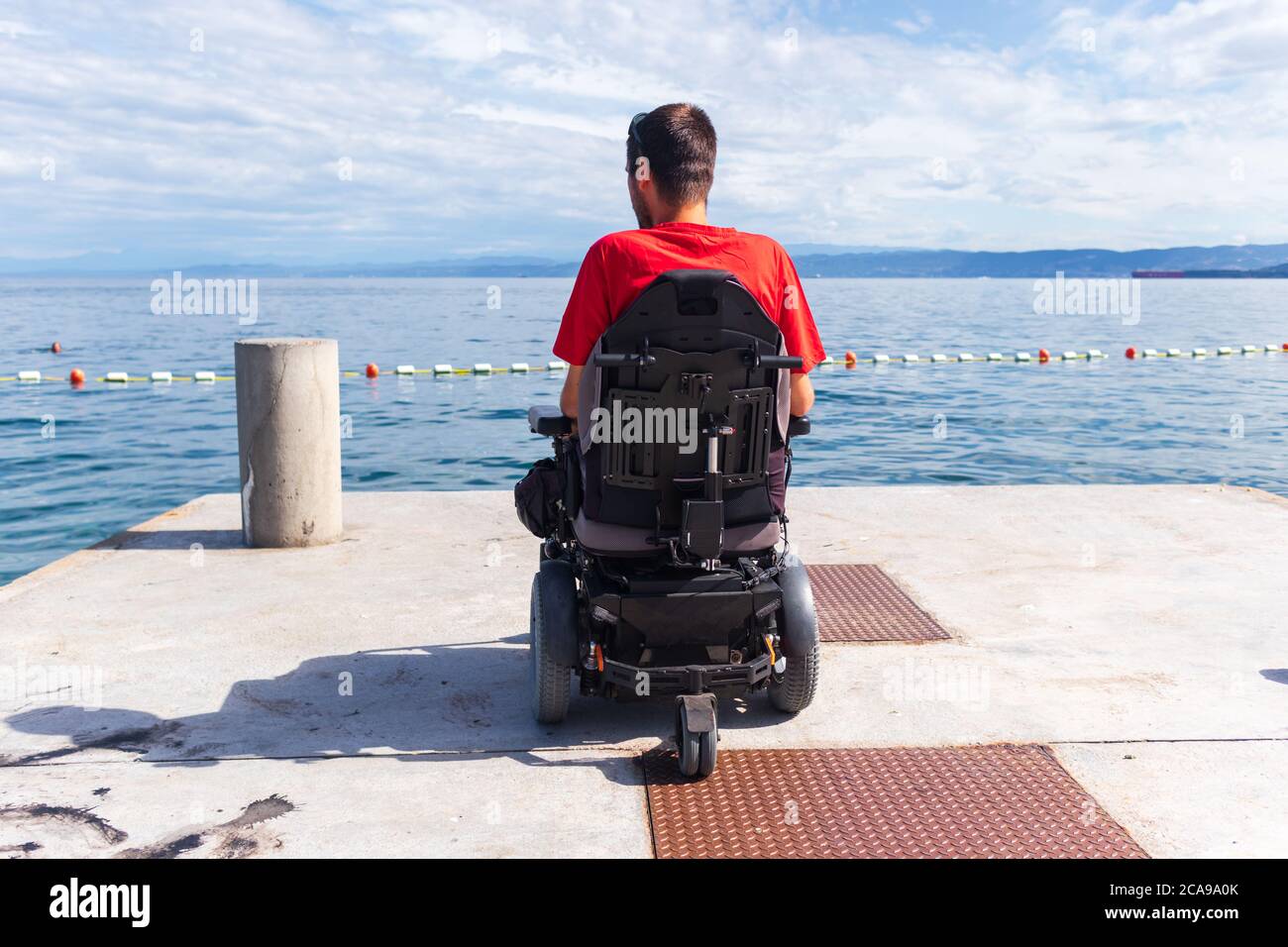 Man sitting in a wheelchair on the beach. Dangers of jumping into water ...