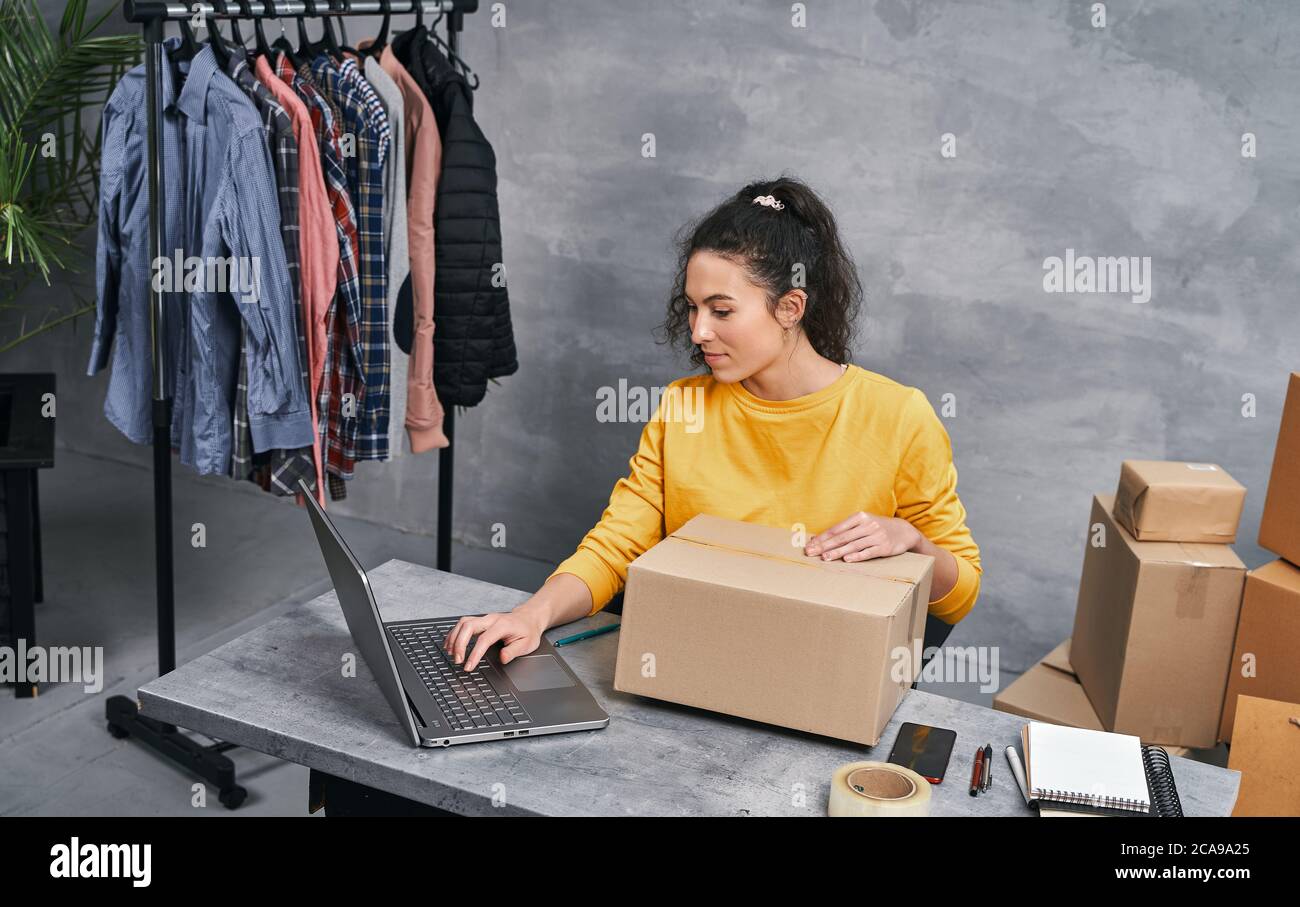 Woman sending parcel using her laptop. Working from home Stock Photo ...