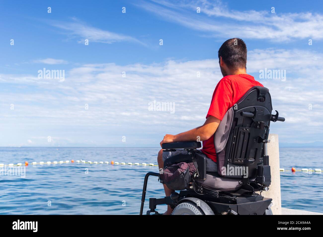 Man sitting in a wheelchair on the beach. Dangers of jumping into water ...