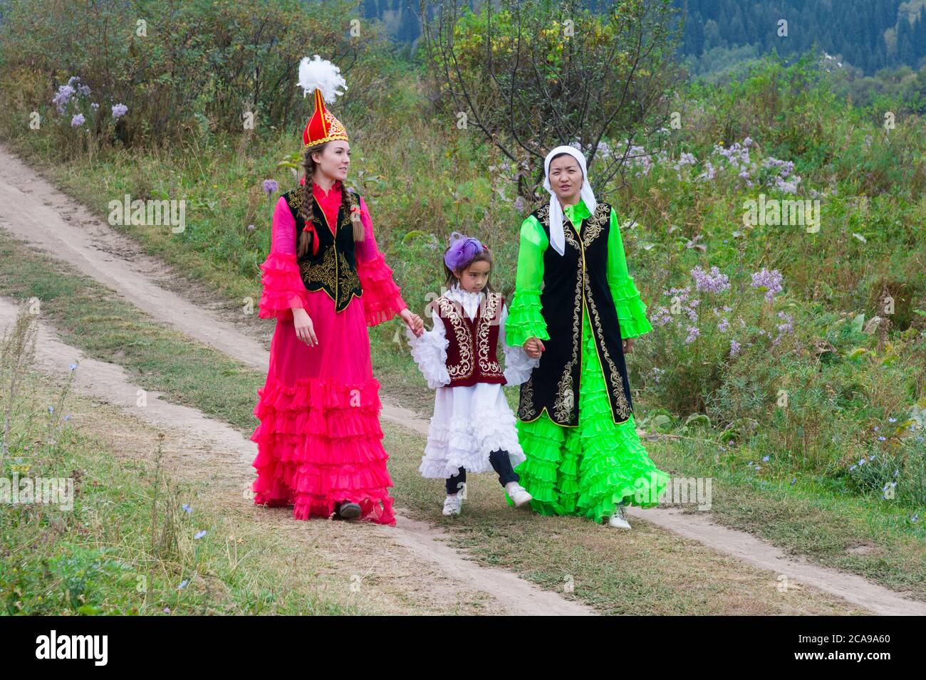 Two Kazakh women walking with a child, Kazakh ethnographical village ...