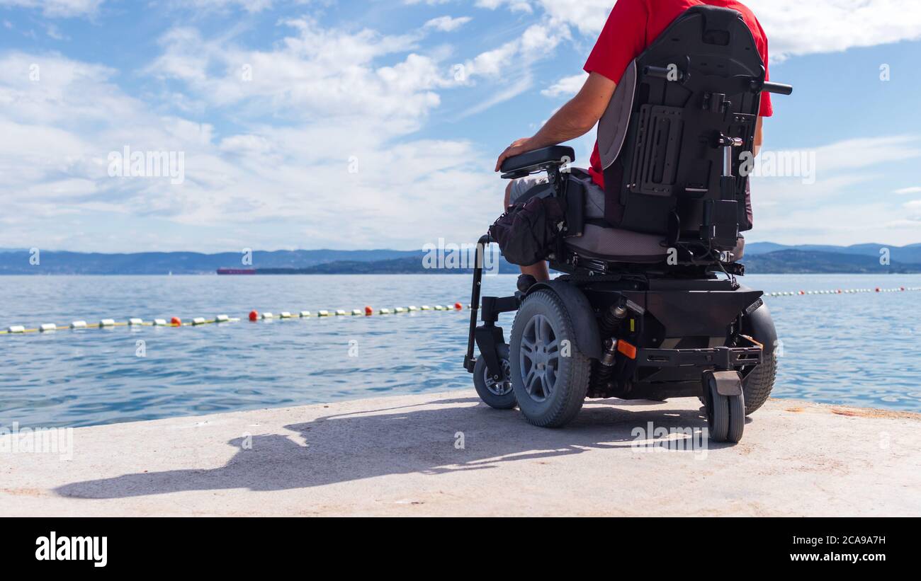 Man sitting in a wheelchair on the beach. Dangers of jumping into water ...