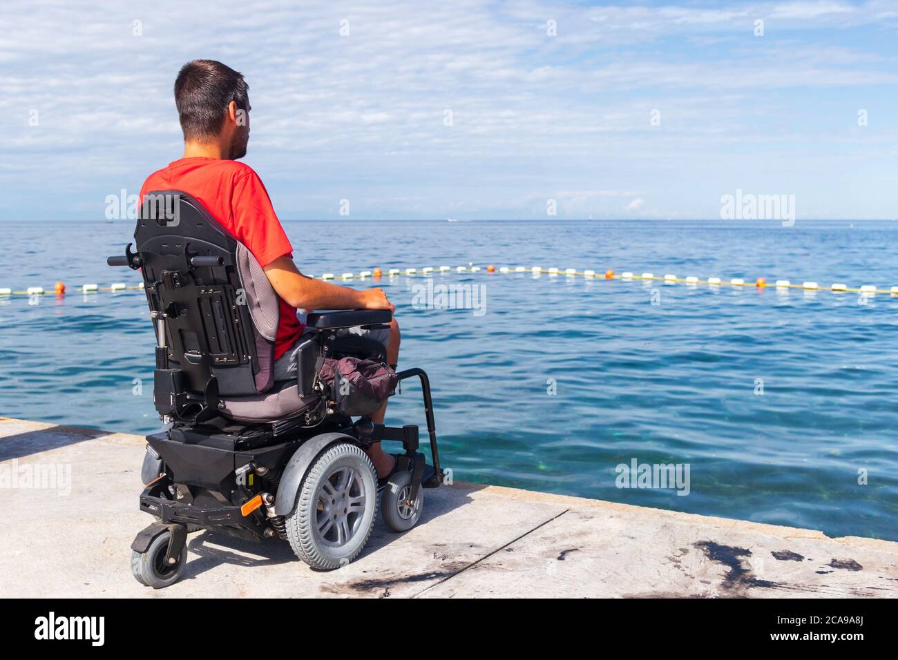 Man sitting in a wheelchair on the beach. Dangers of jumping into water ...