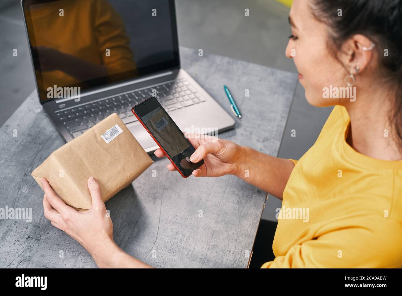 Woman scans code on the parcel using her phone camera Stock Photo - Alamy