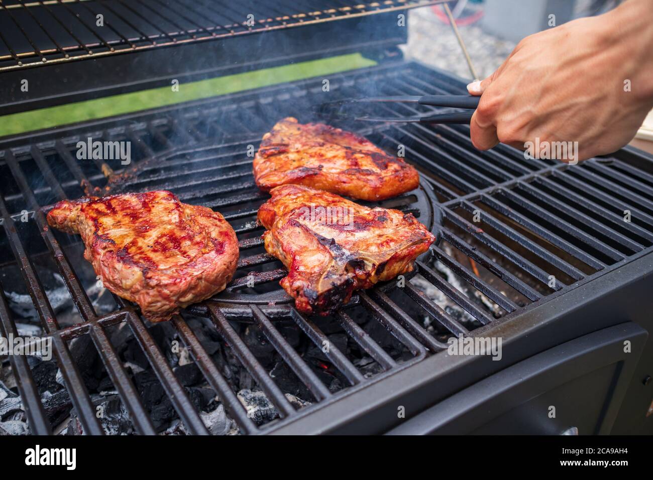 Home barbecue with charcoal in the backyard grilling steaks and other ...