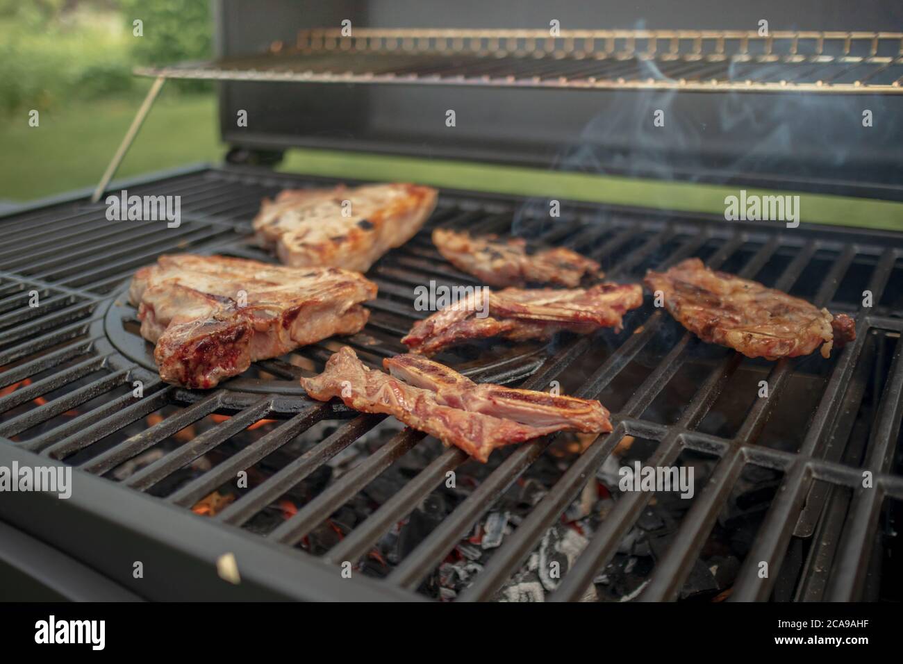 Home barbecue with charcoal in the backyard grilling steaks and other ...