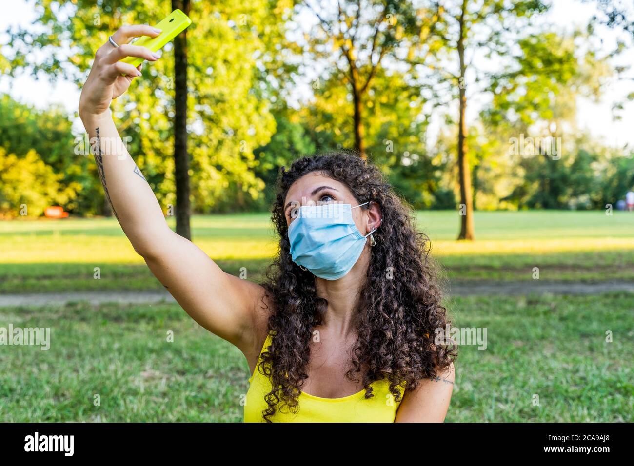 pretty young woman taking a selfie wearing an anti contagion face mask ...