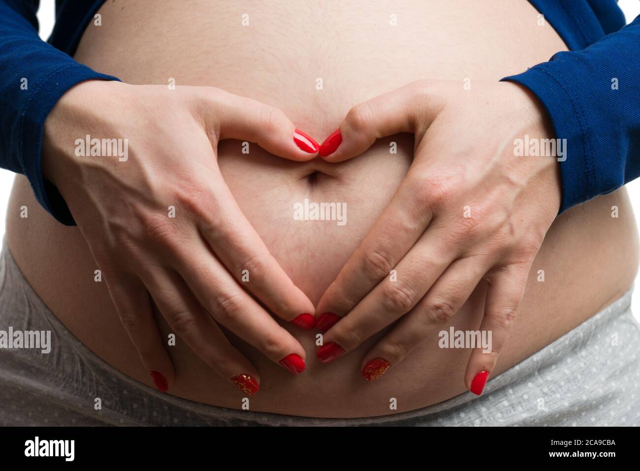 Close-up of future mom making heart shape on her tummy as love symbol ...