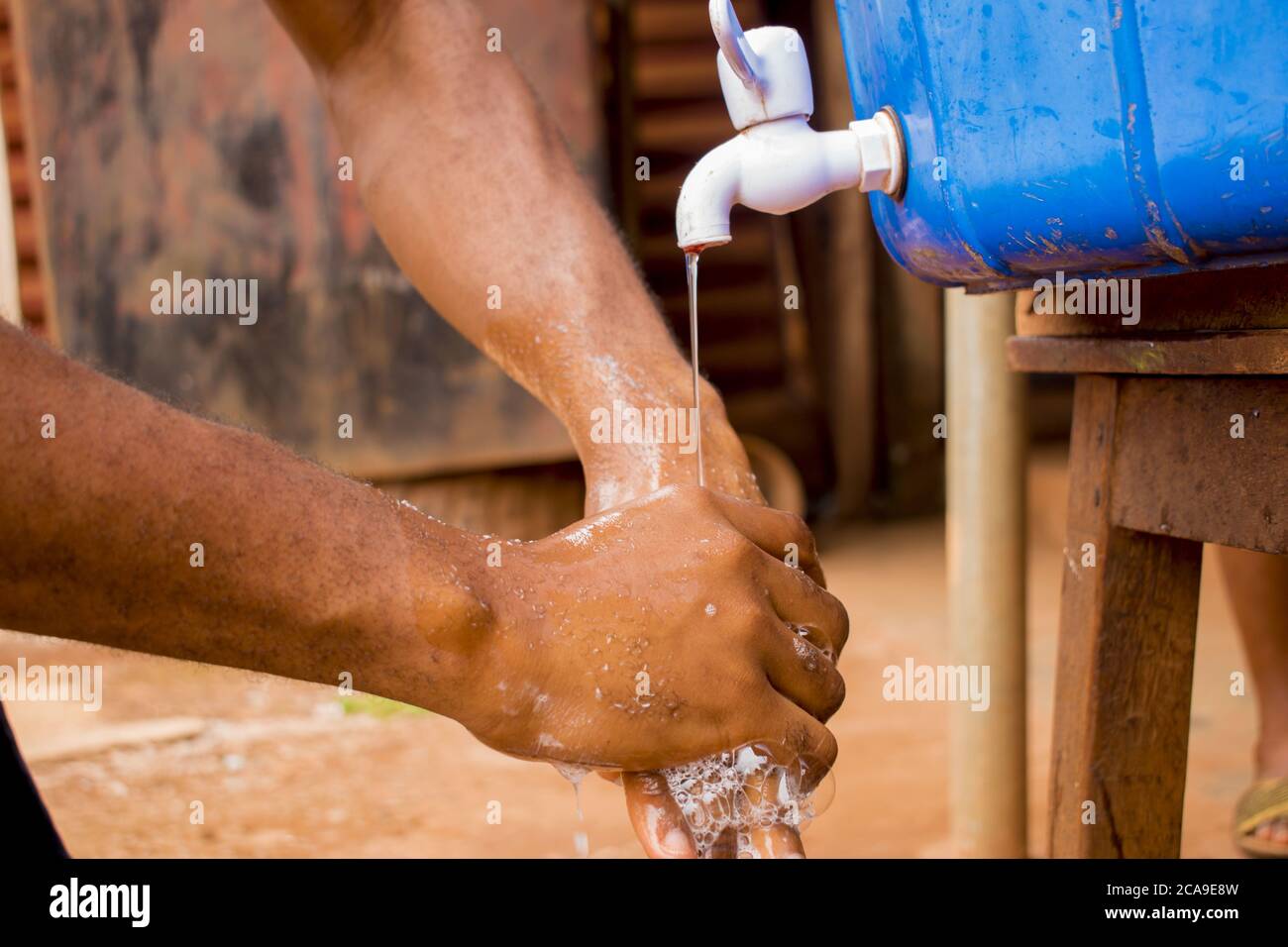 Closeup shot of a black male washing is hands from a water container ...