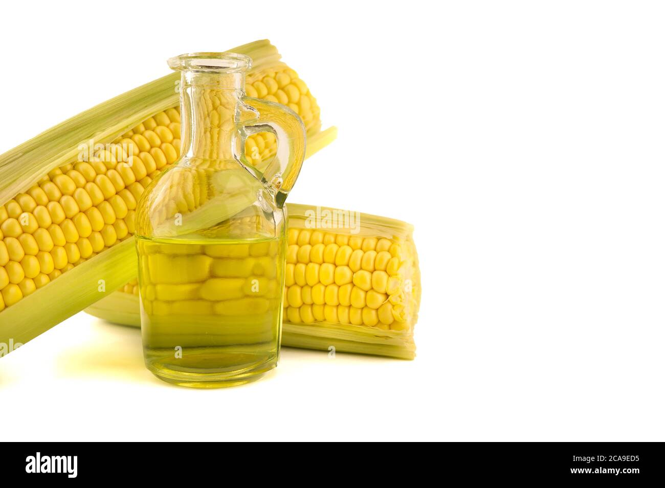 Corn oil in decanter and fresh corncobs isolated on white background ...
