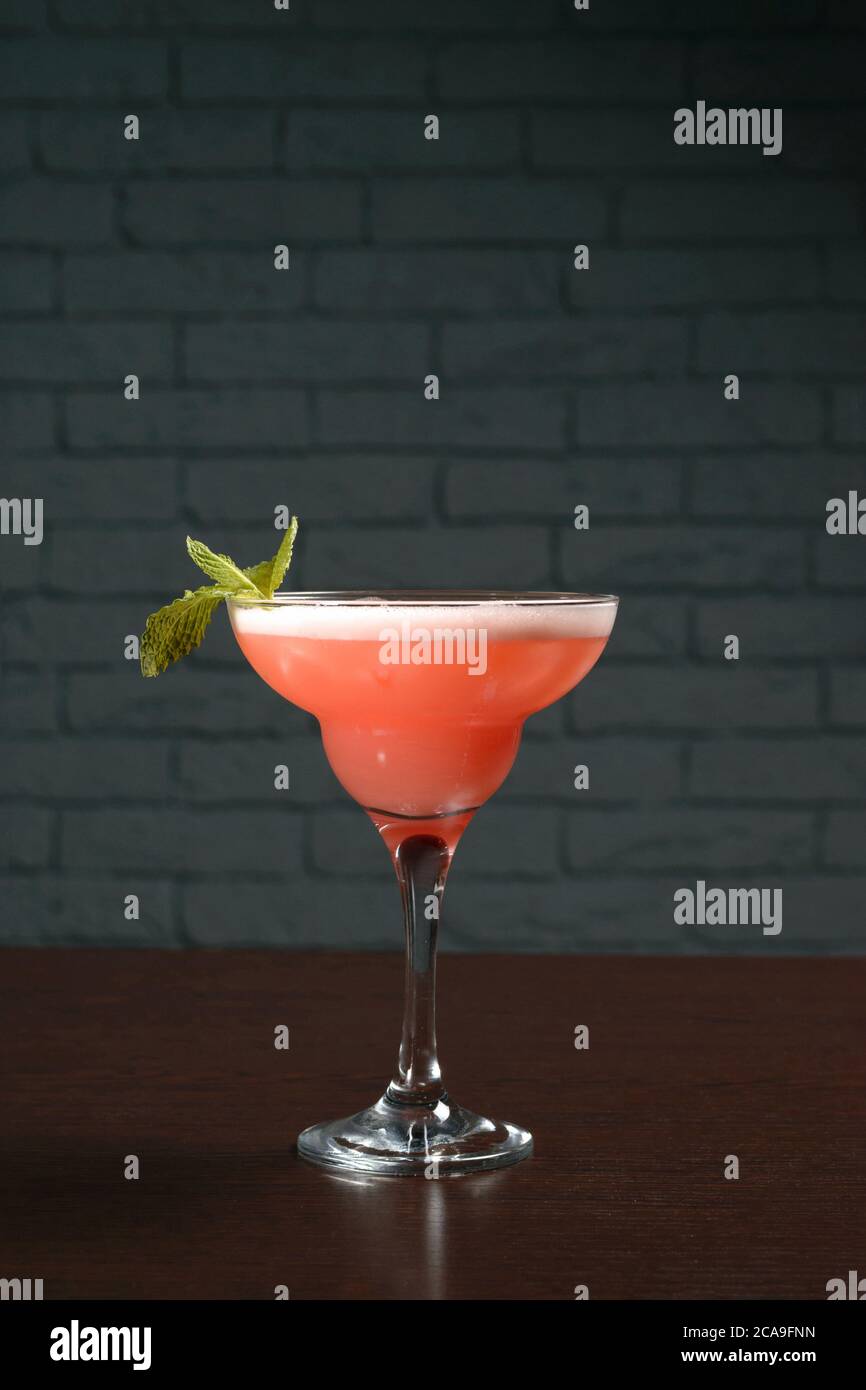 Pink cocktail in a glass on a wooden table against a brick wall. Photos ...