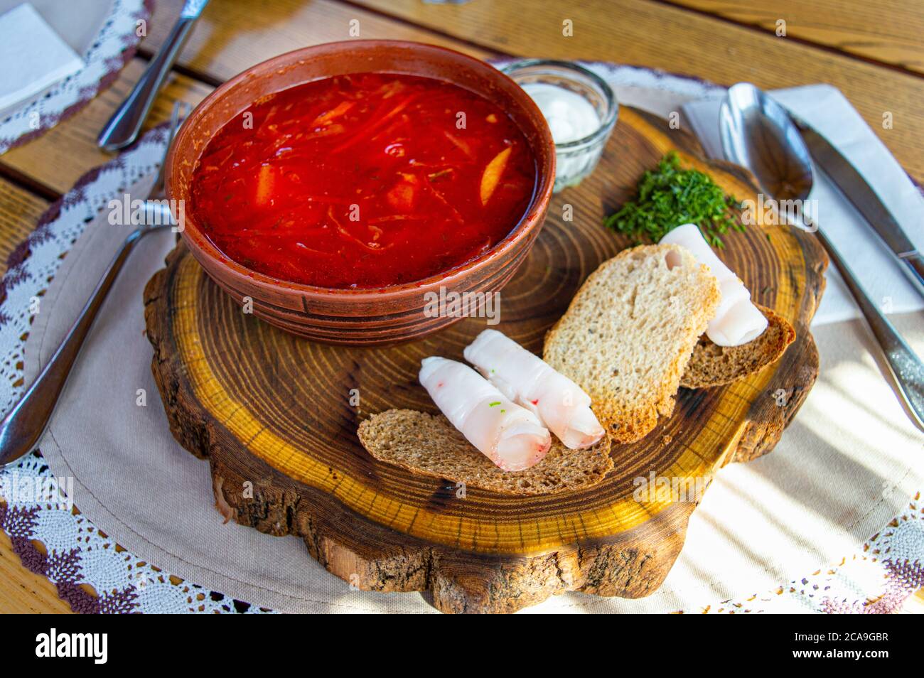 Beet soup in ceramic plate with becon, bread and sour cream on wooden ...