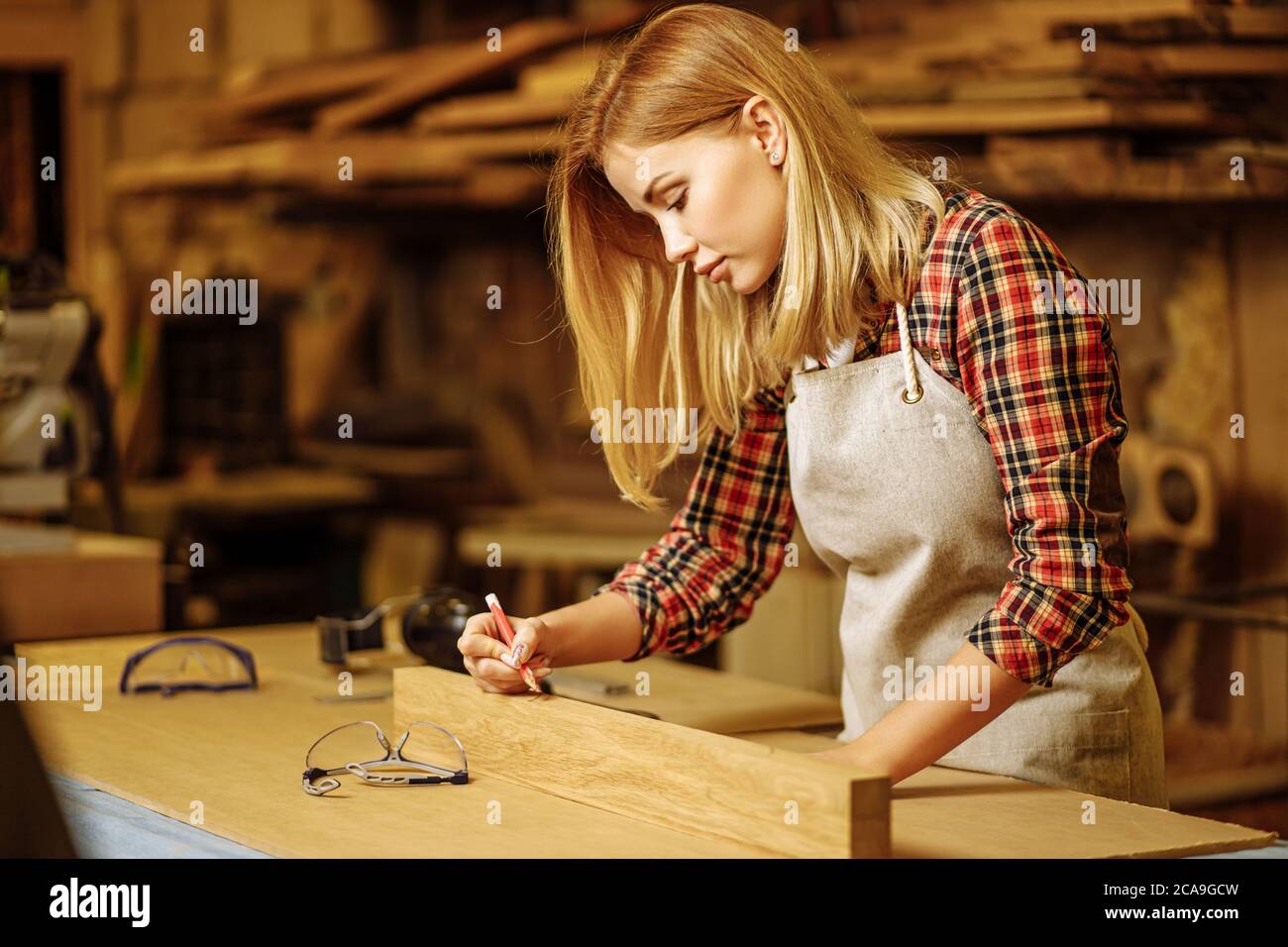 pretty hardworking carpenter woman at workplace, she use pencil for ...