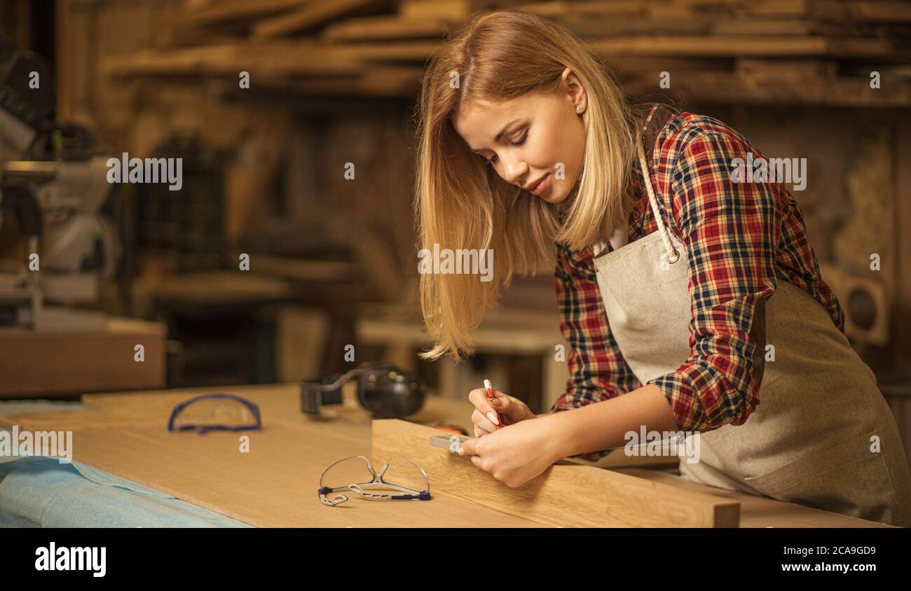 portrait of beautiful caucasian woman carpenter dealing with handicraft ...