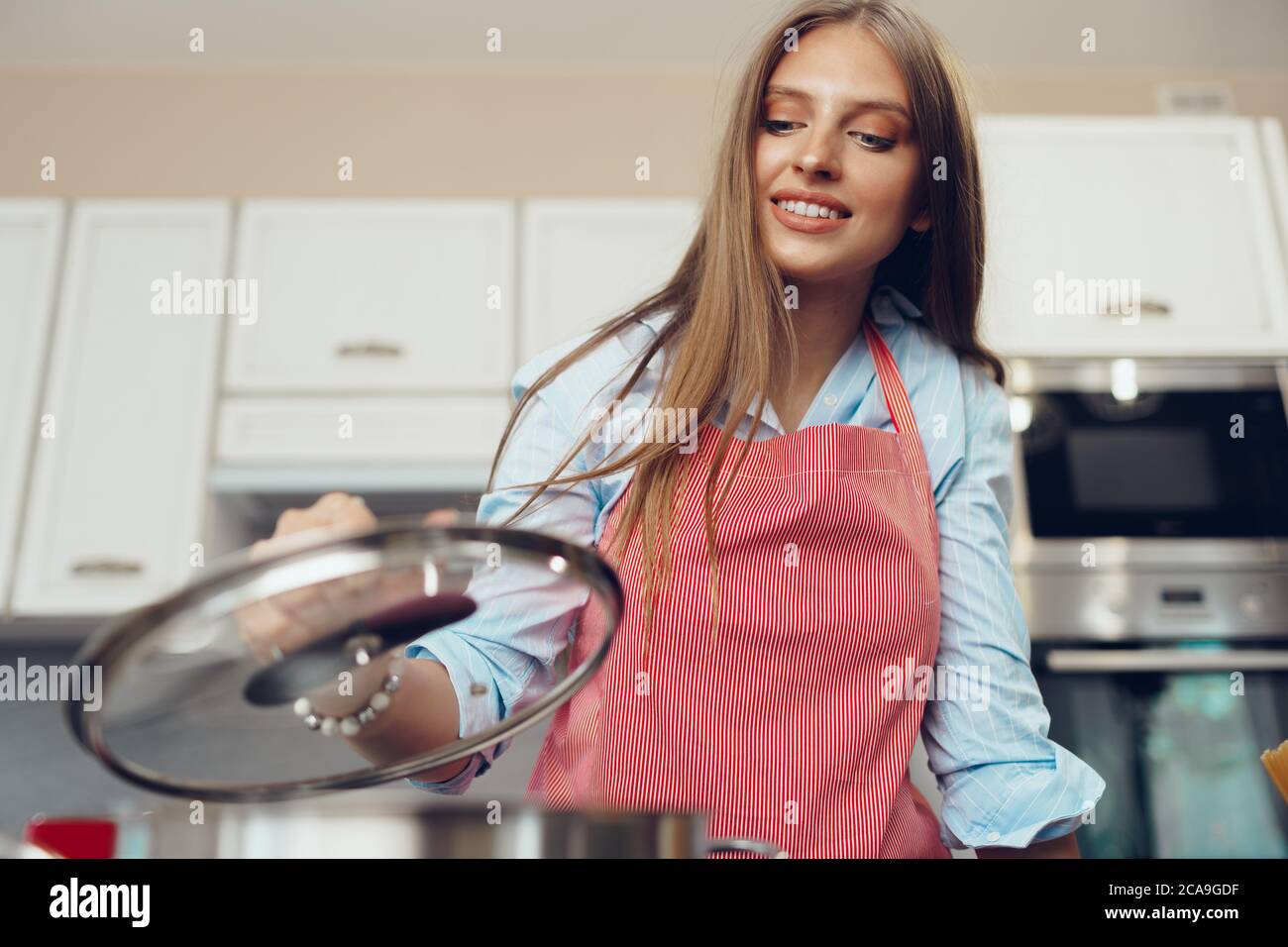 Nice young woman cooking something by the stove in her kitchen Stock ...