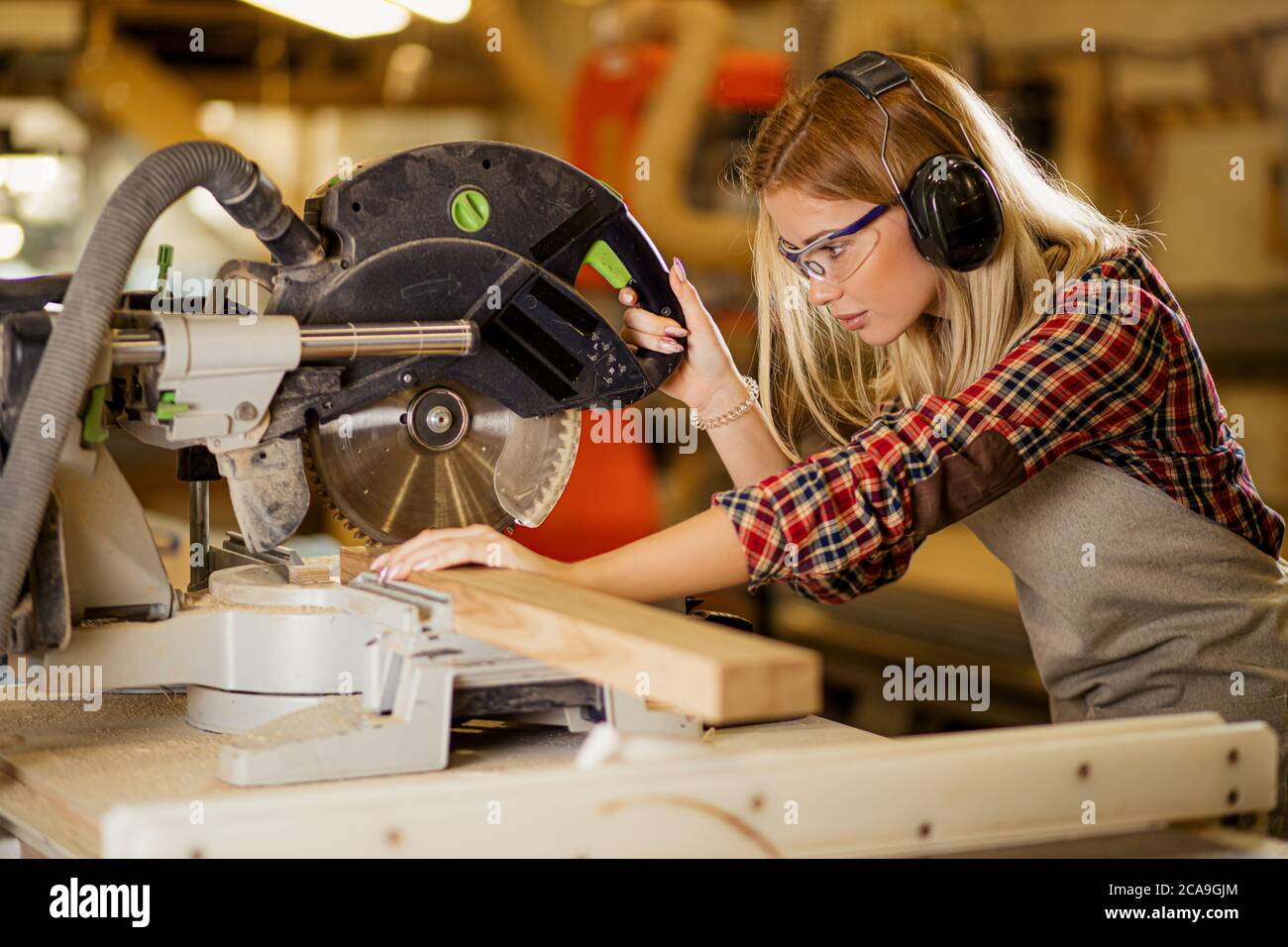 concentrated woman carpenter behind powerful electric machine, woman ...