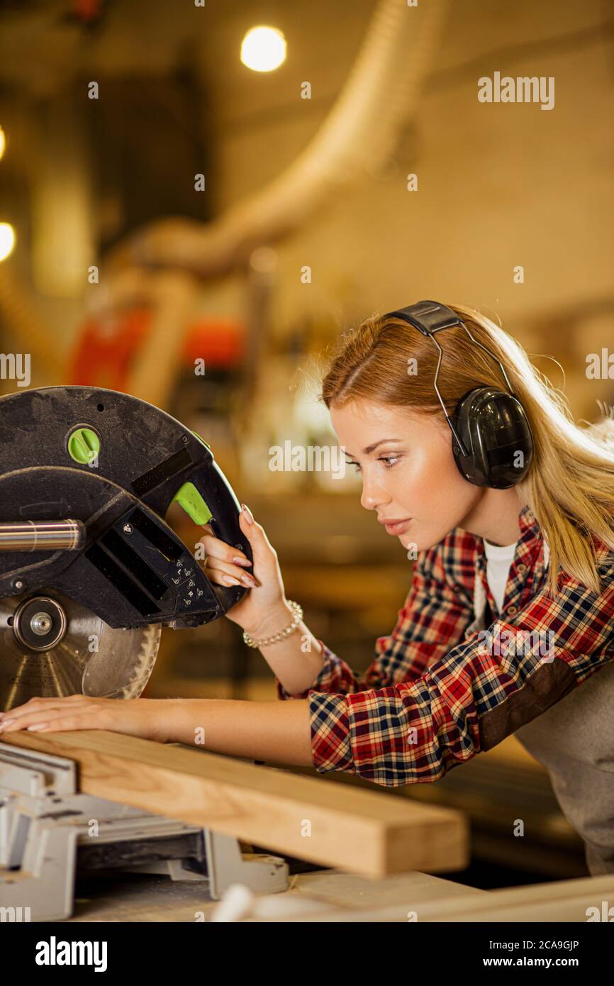 concentrated woman carpenter behind powerful electric machine, woman ...