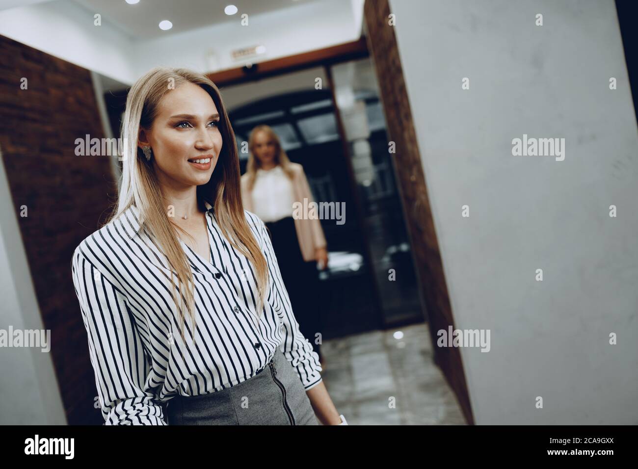 Two young women in formal clothes entering hotel lobby Stock Photo - Alamy