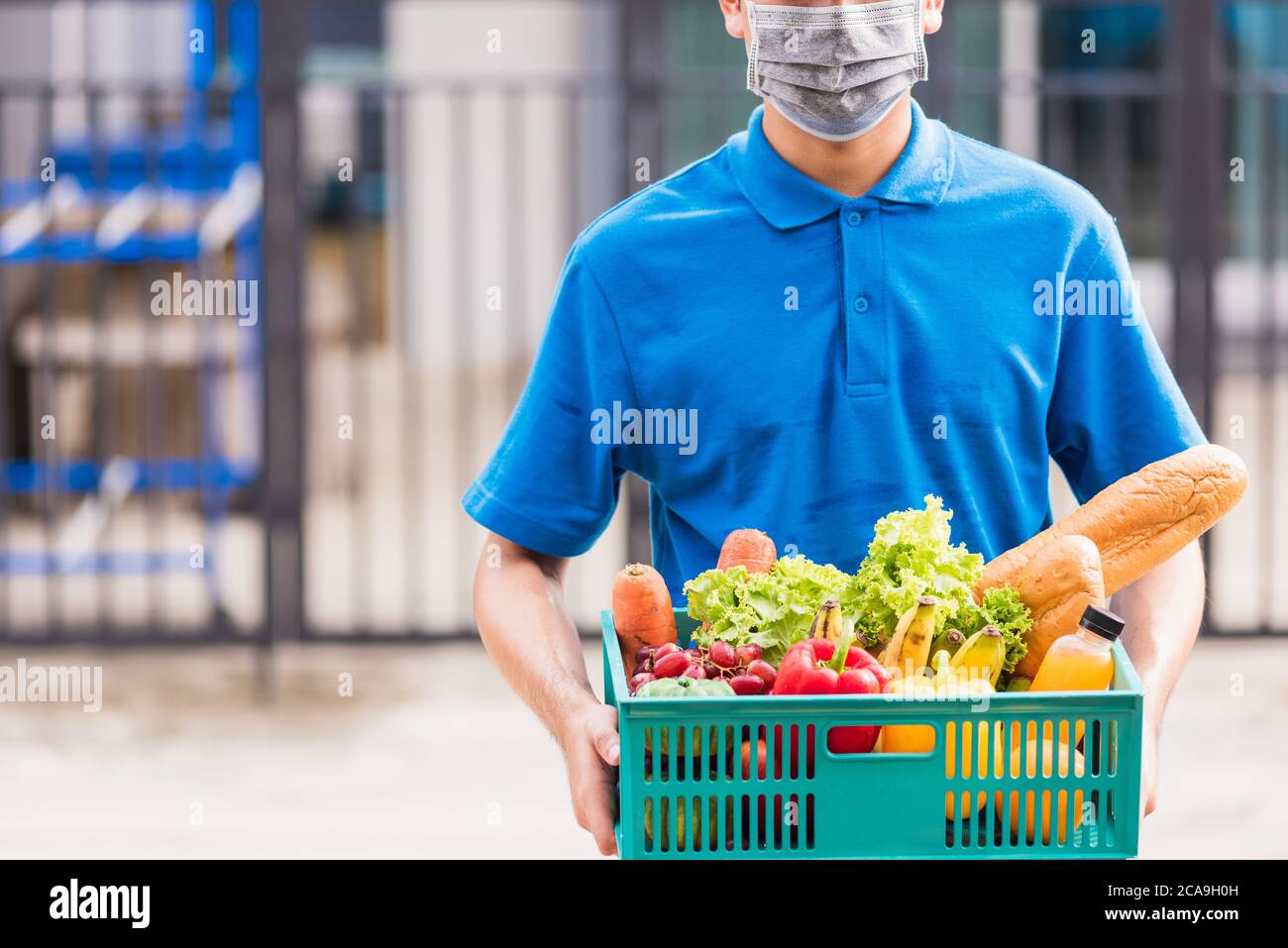Asian grocery store delivery man wearing blue uniform and face mask ...