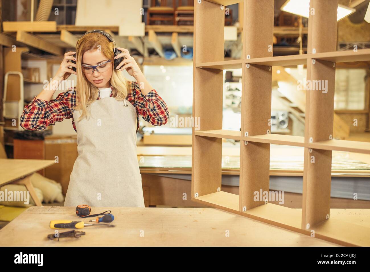 caucasian female woodworker wearing headphones during work, woman in ...