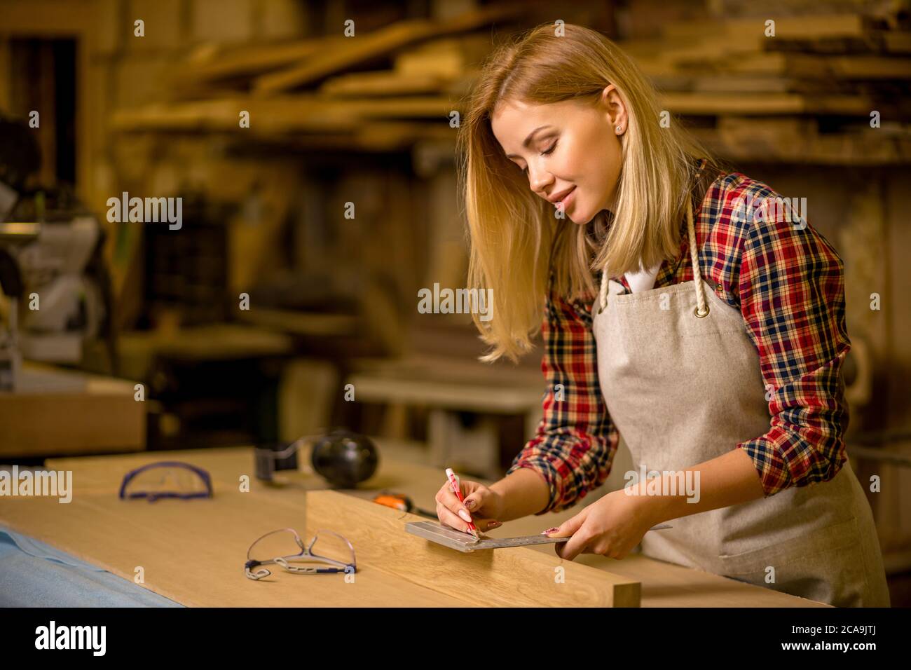 portrait of professional woodworker making marks on wooden piece, woman ...