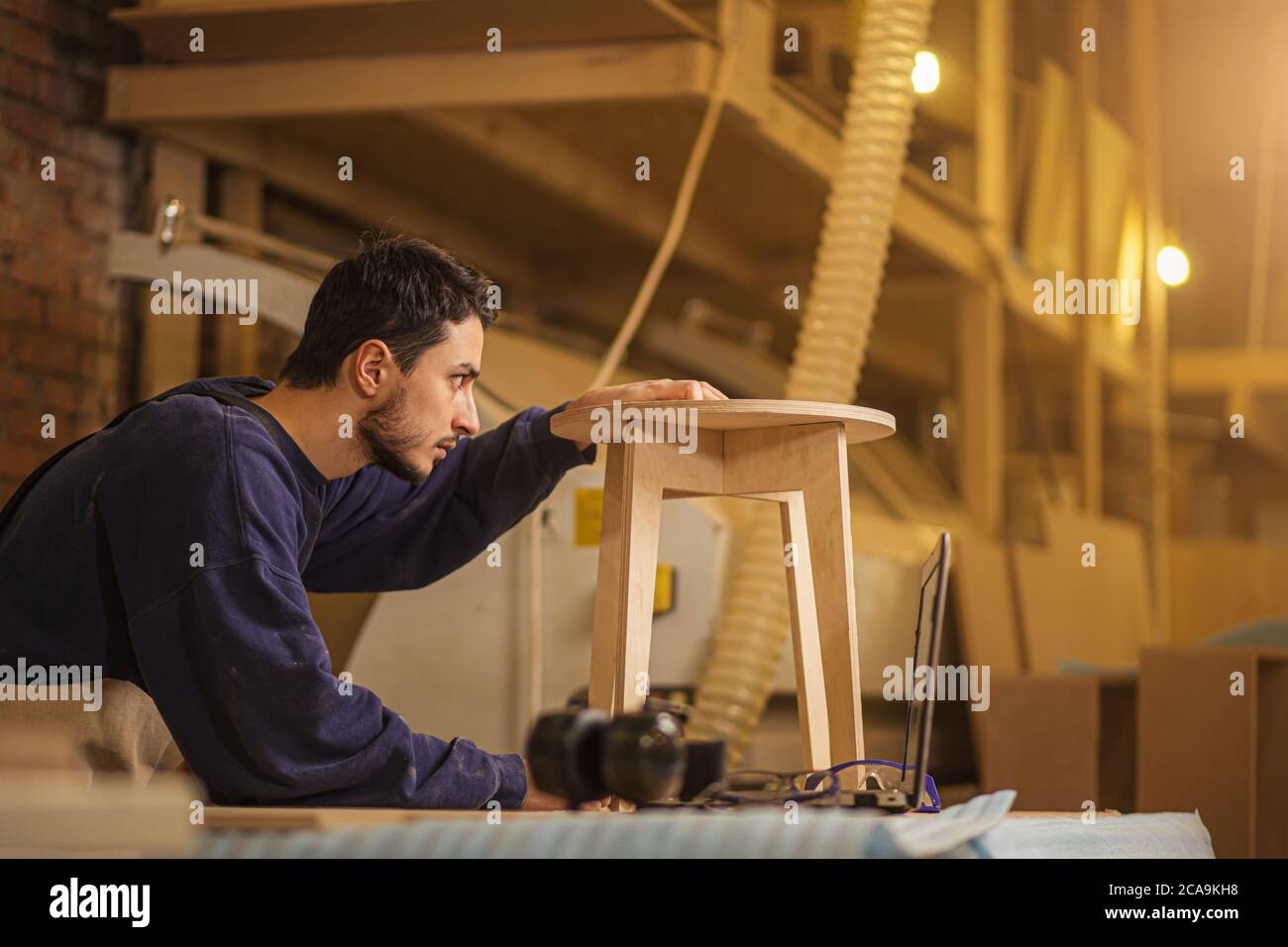 portrait of young cerpenter checking handmade wooden chair after ...