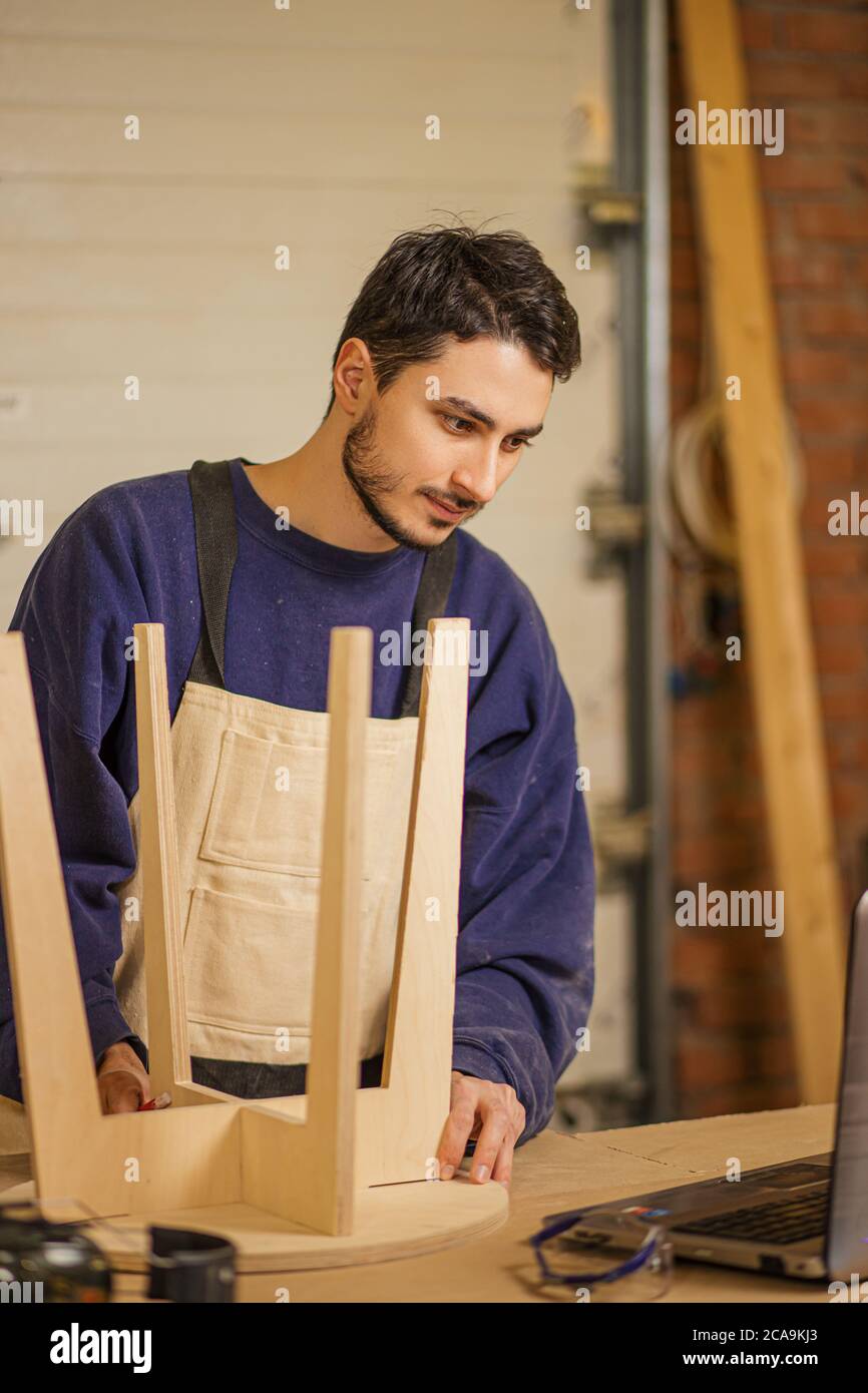 serious caucasian carpenter deals with making wooden chair in workshop ...
