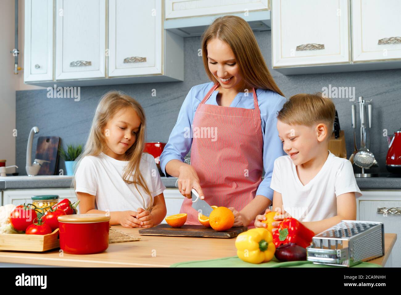 Mother cooking with her children in kitchen Stock Photo - Alamy