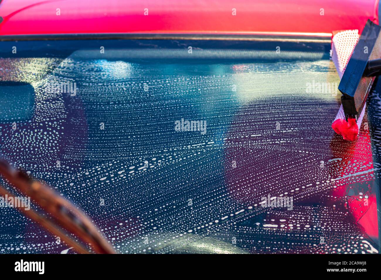 Washing and cleaning the front window of a car with mop in self service ...
