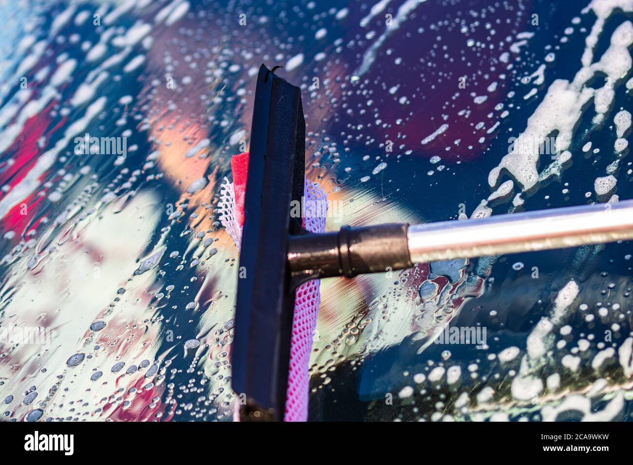 Washing and cleaning the front window of a car with mop in self service ...