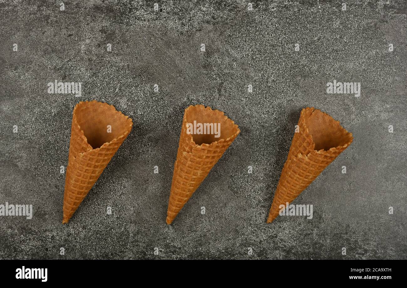 Close up three empty wafer ice cream cones on gray table, elevated top ...