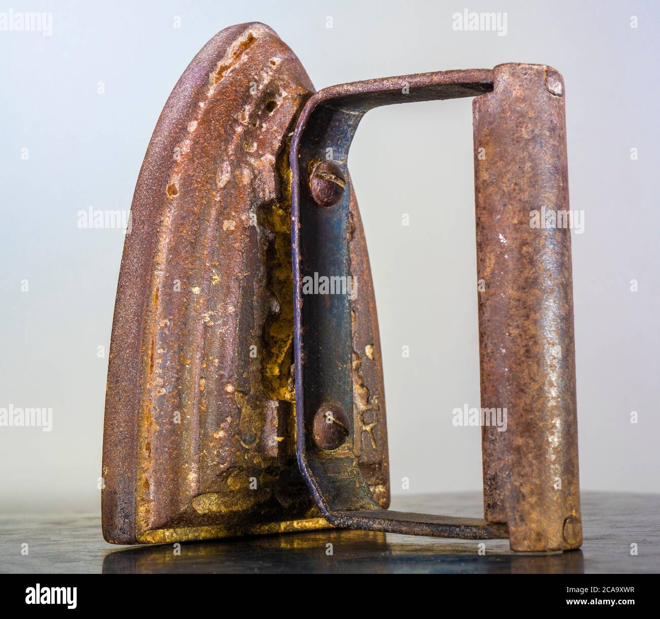 A rusty and pitted, old flat British iron, with two large screws ...