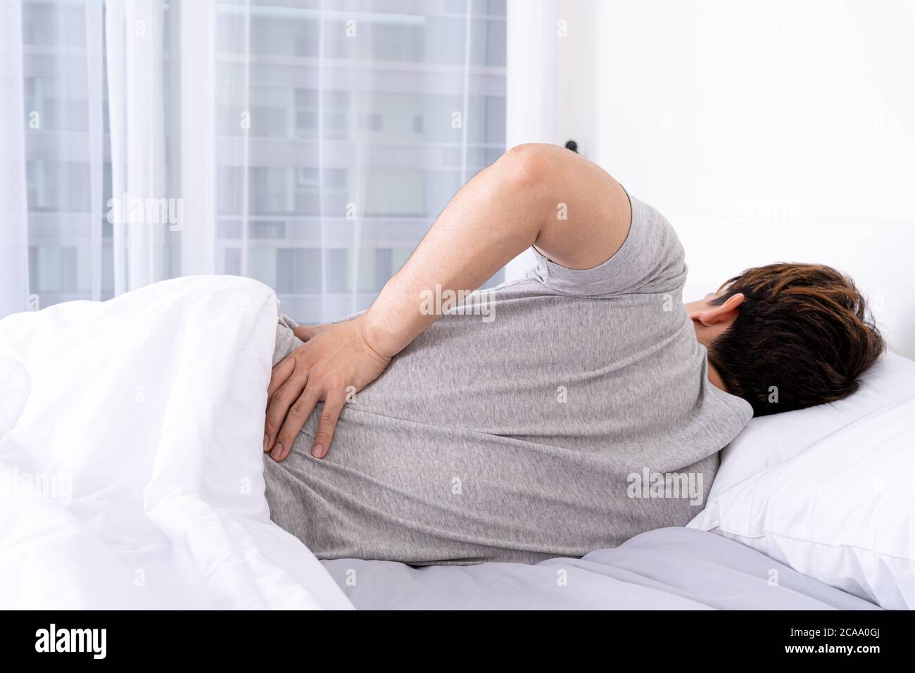 Young man suffering back pain from uncomfortable bed. Healthcare ...