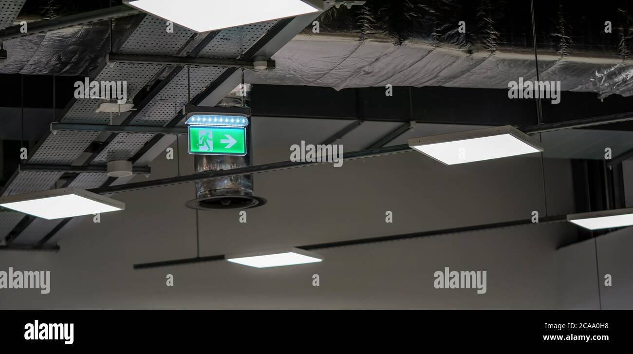 Illuminated green emergency / fire exit sign with running man pictogram ...