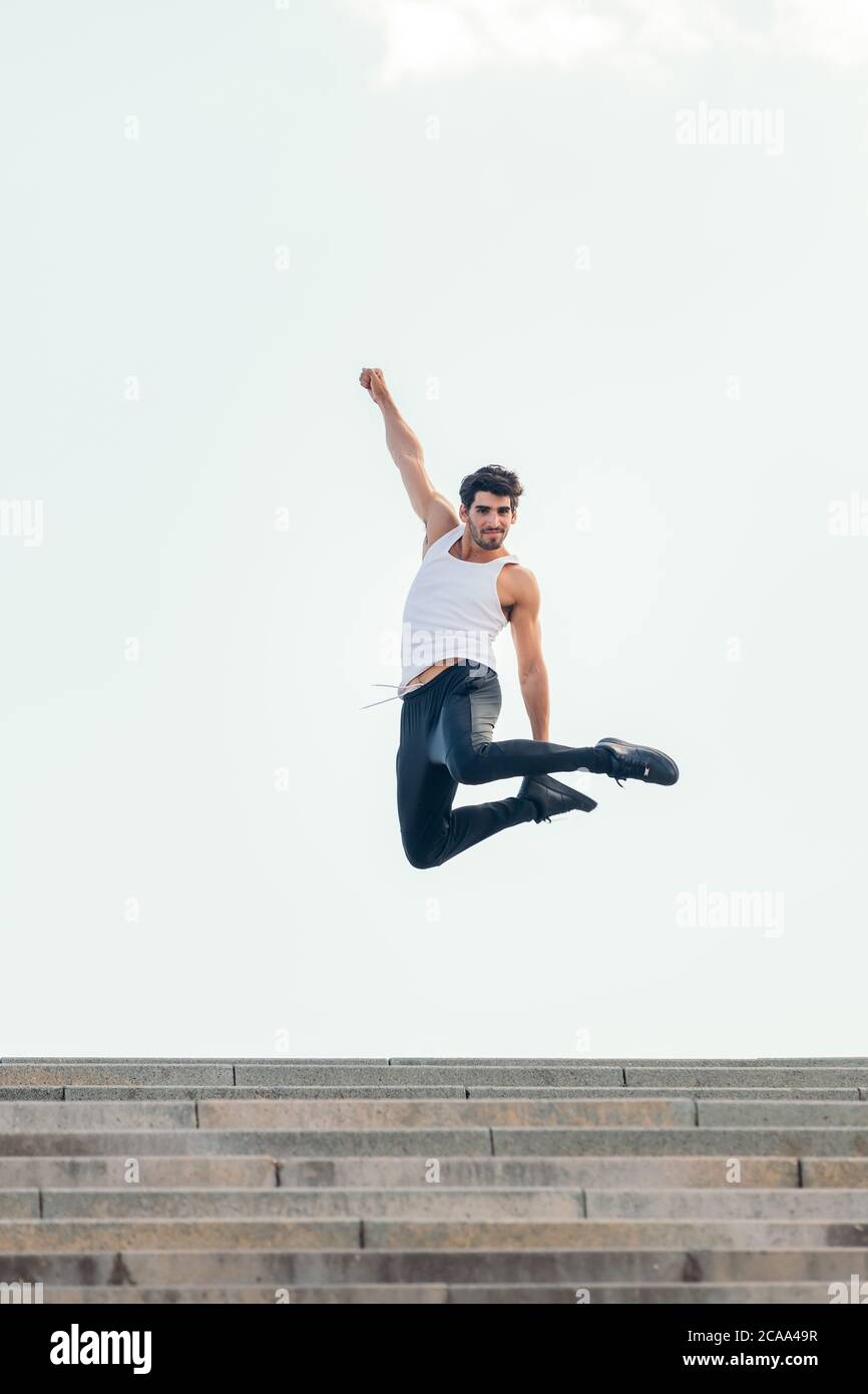 vertical photo of a handsome sportsman jumping up at the top of a ...