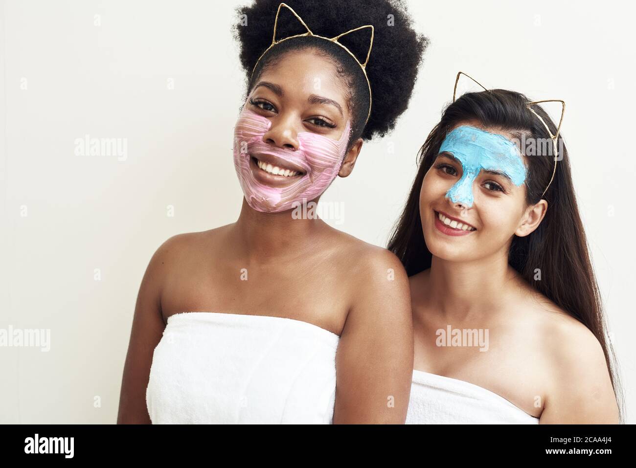 Multimasking. Two different ethnic young women are hugging. Women's ...