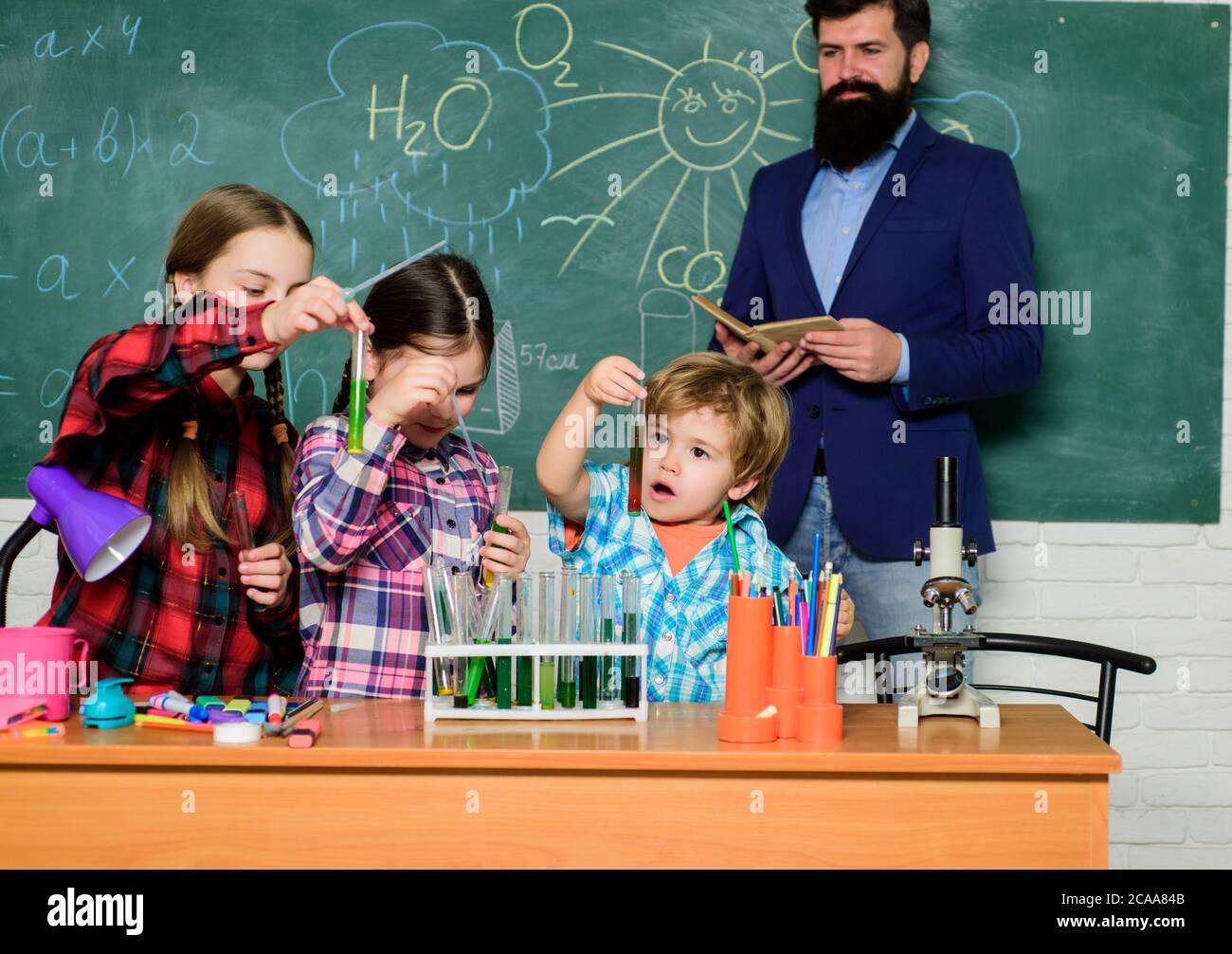 Topic of our club. Teacher and pupils test tubes in classroom ...