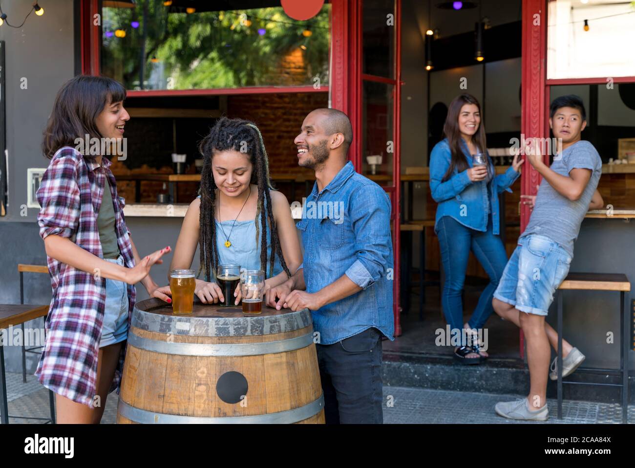 A group of friends standing outdoor at a brewery barrel while having ...