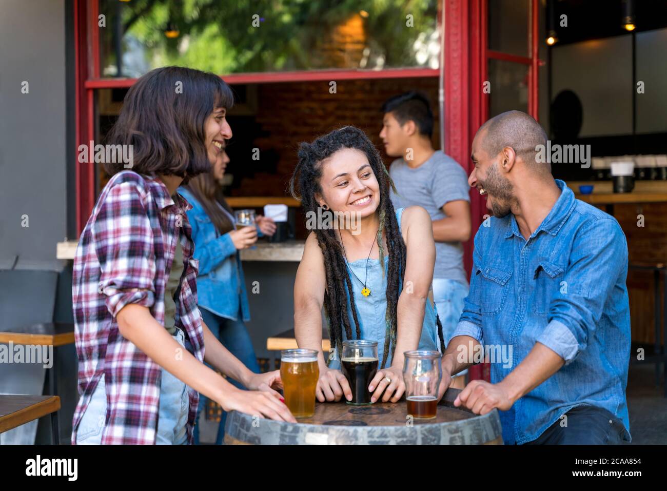 A group of friends standing outdoor at a brewery barrel while having ...