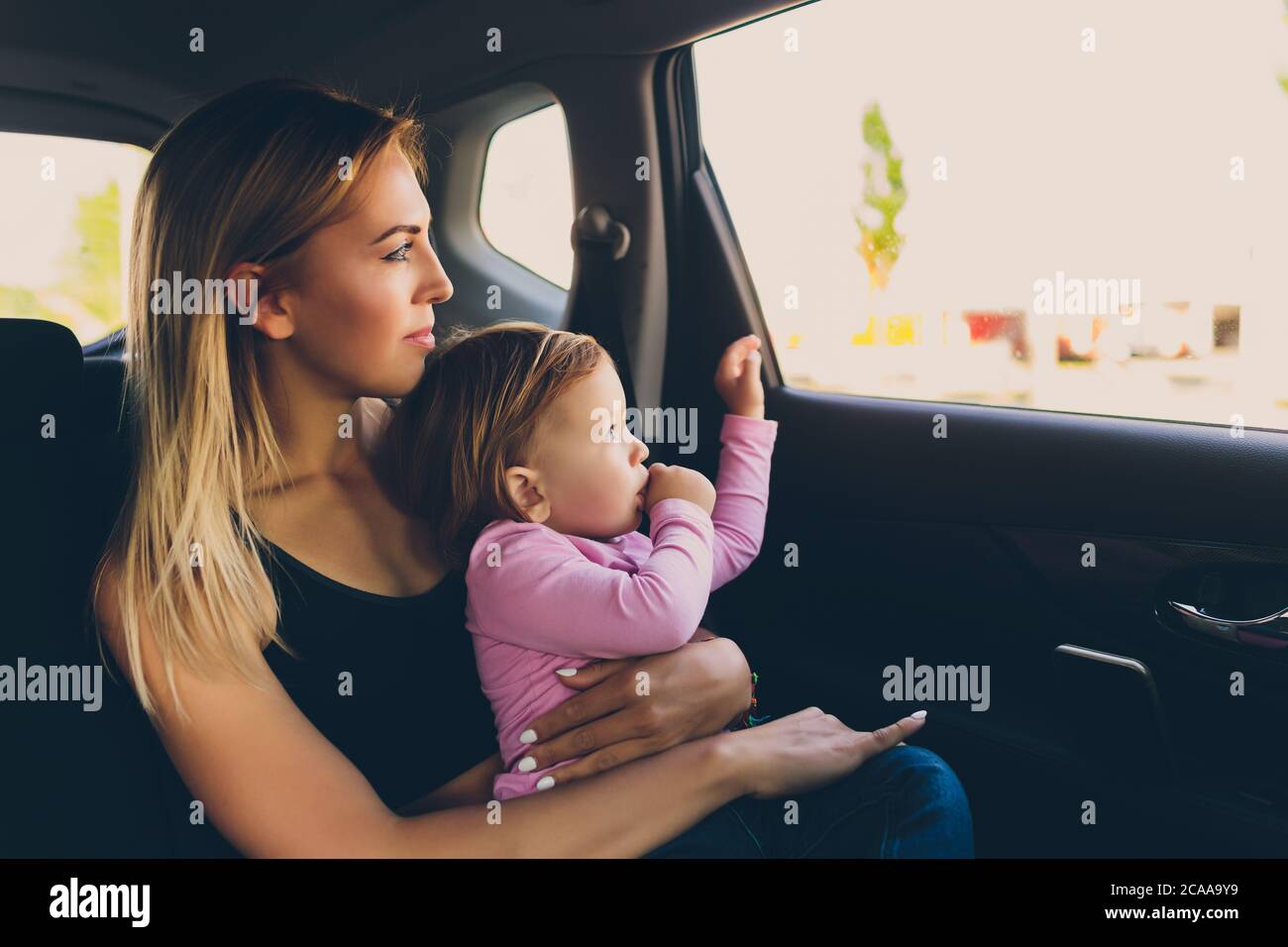 Little baby toddler girl looks out of the car window with her mom Stock ...