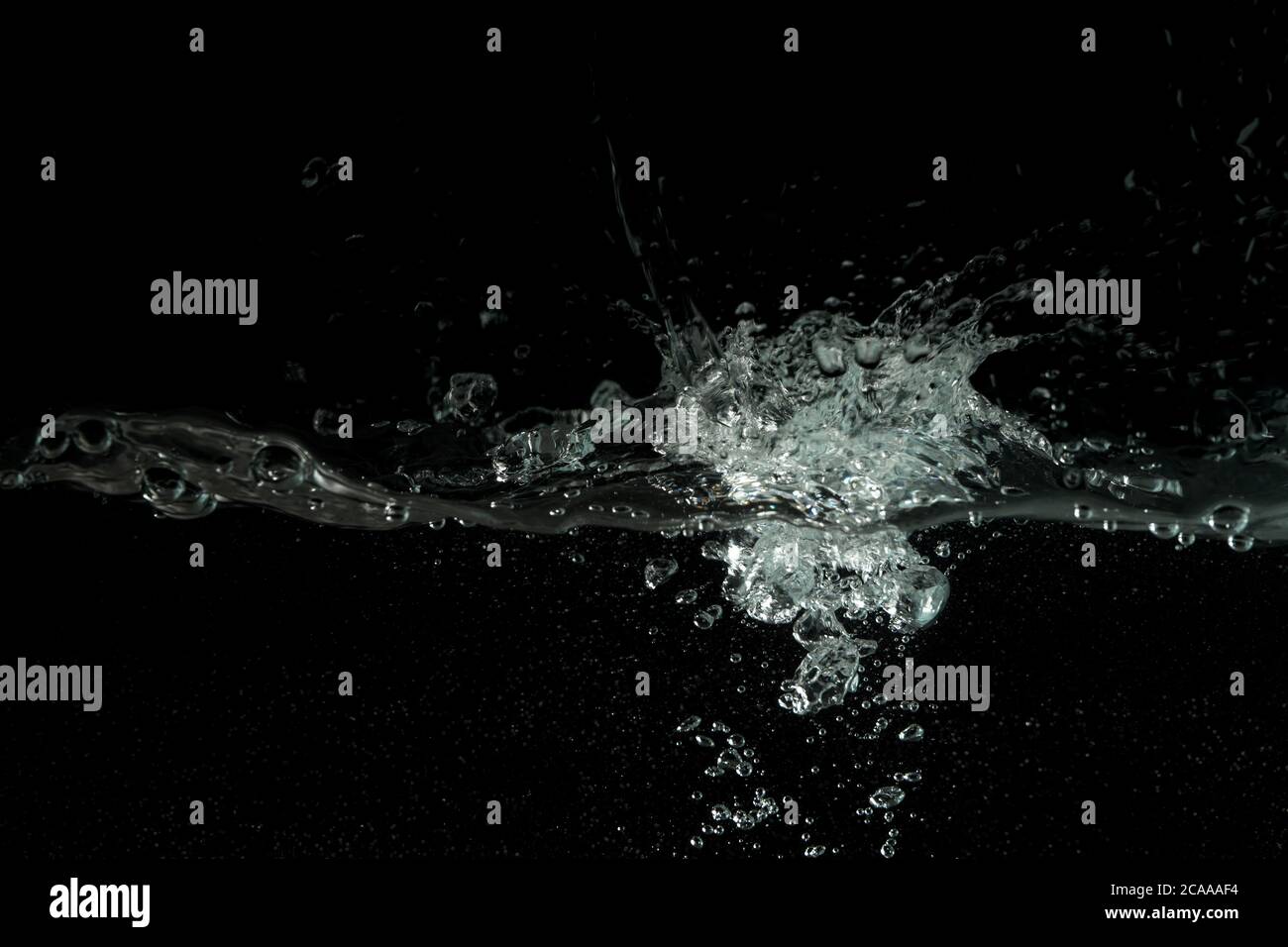 Water splashing as it's poured into aquarium tank, black background ...