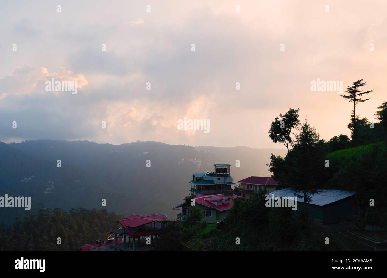 Sunset over local house and rooftops with view of pine forest and ...