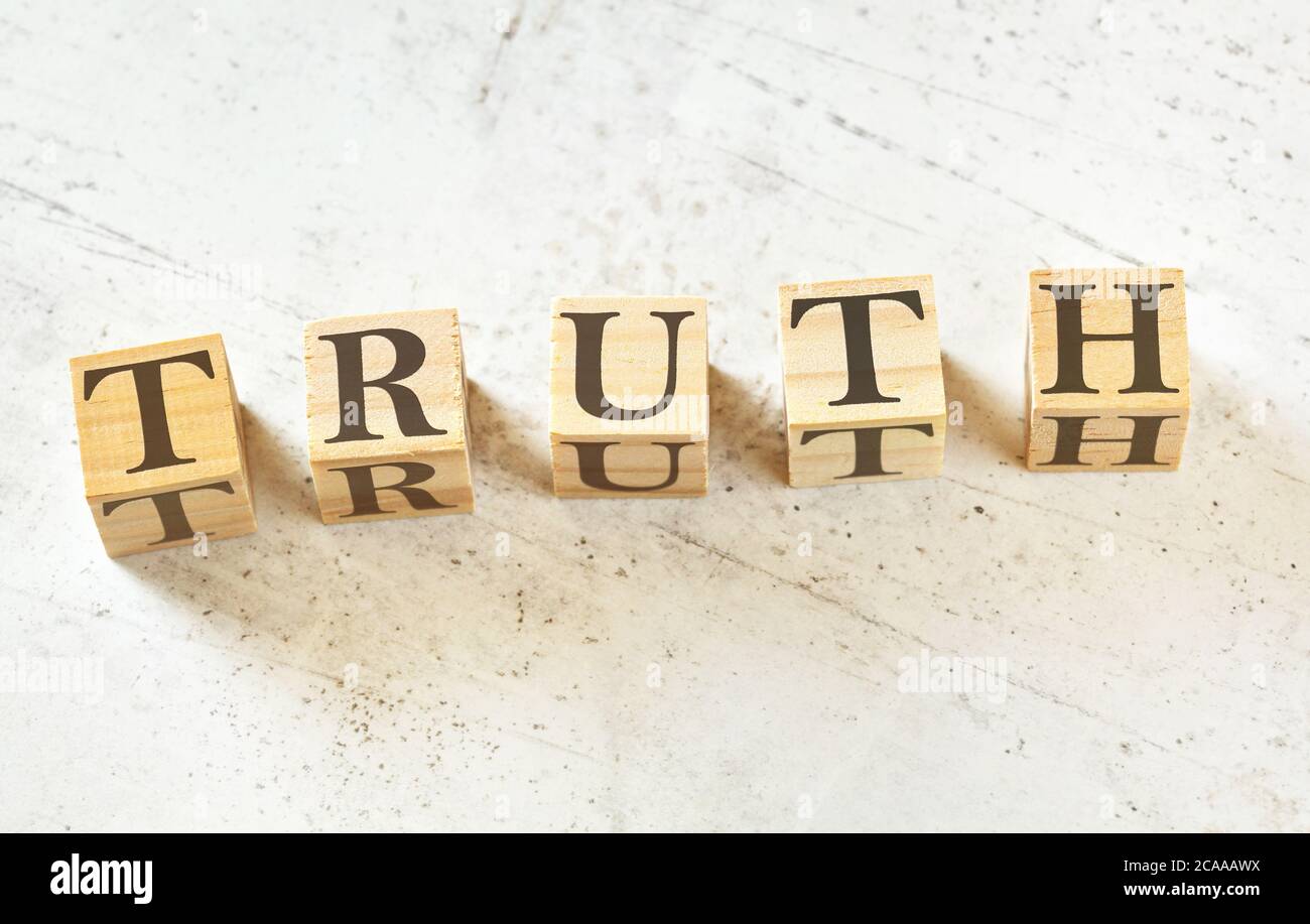Five wooden cubes with word TRUTH on white stone like board, view from ...
