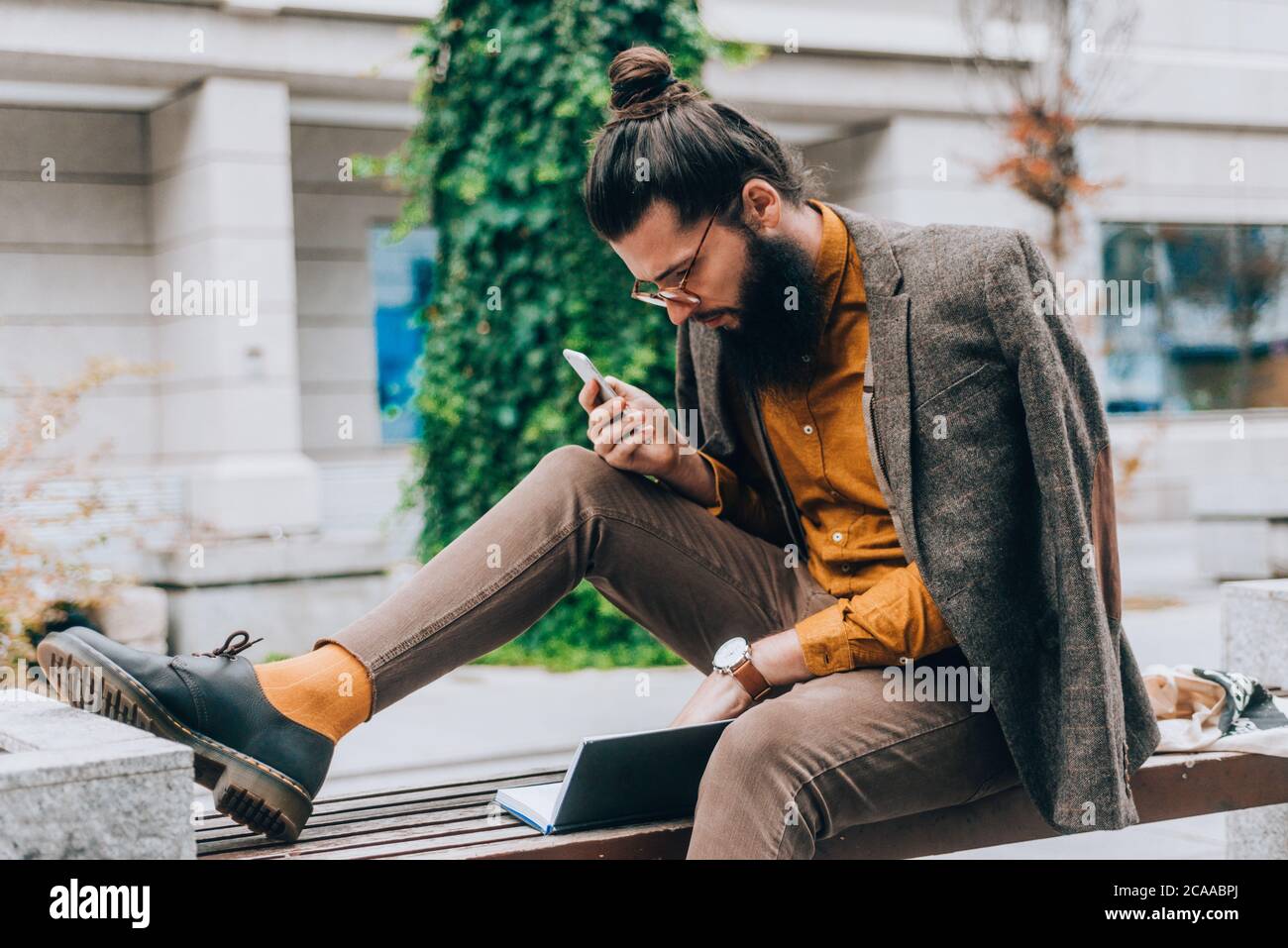 Modern day hipster reading a book at the city square during daytime ...