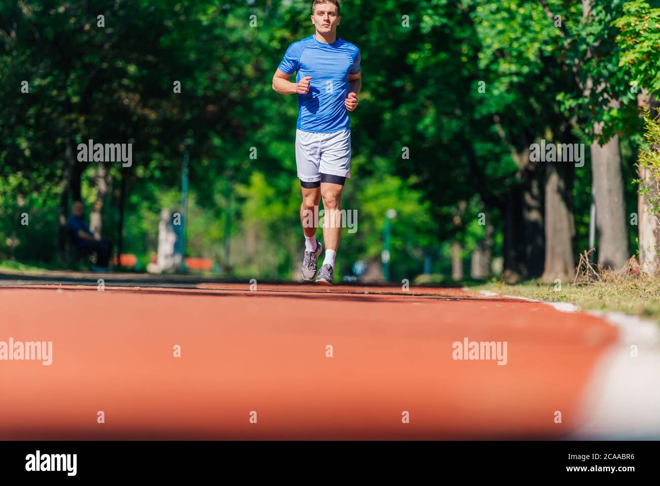 Strong athletic man jogging on the running track Stock Photo - Alamy