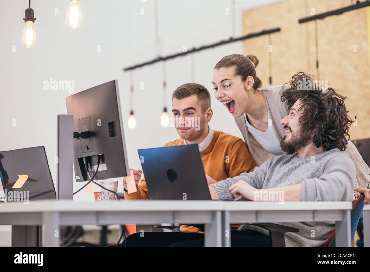 Happy surprise for the teammates. Coworkers cheering while looking at a ...