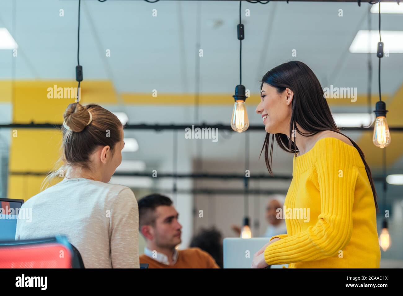 Young business colleagues talking to each other while leaning on a desk ...