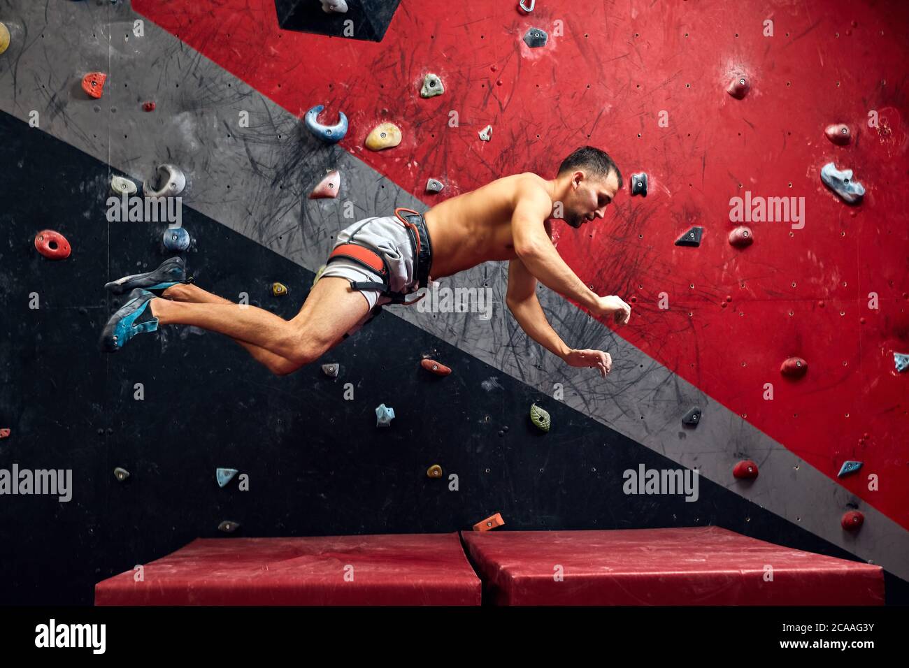 Motion shot of male climber falling on mat from climber wall at an ...